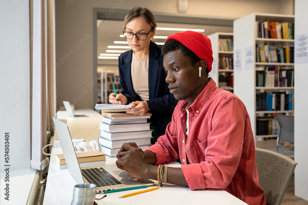 Collaborative learning in higher education. Two diverse students guy and girl using laptop ...