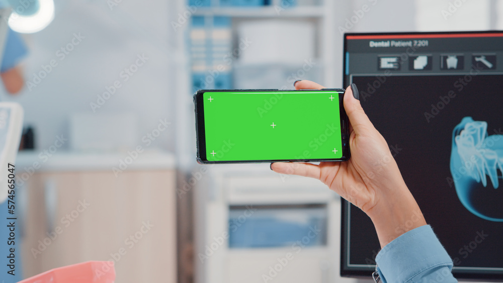 Close up of orthodontist holding horizontal green screen on smartphone ...