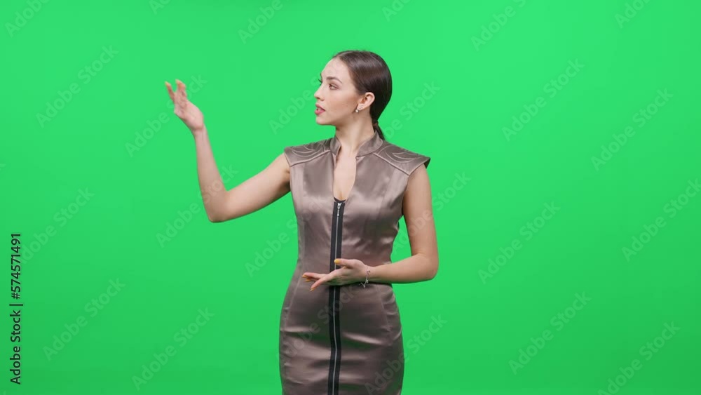 Woman TV presenter in a brown dress stands against the green background ...