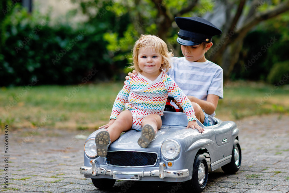 Two happy children playing with big old toy car in summer garden ...