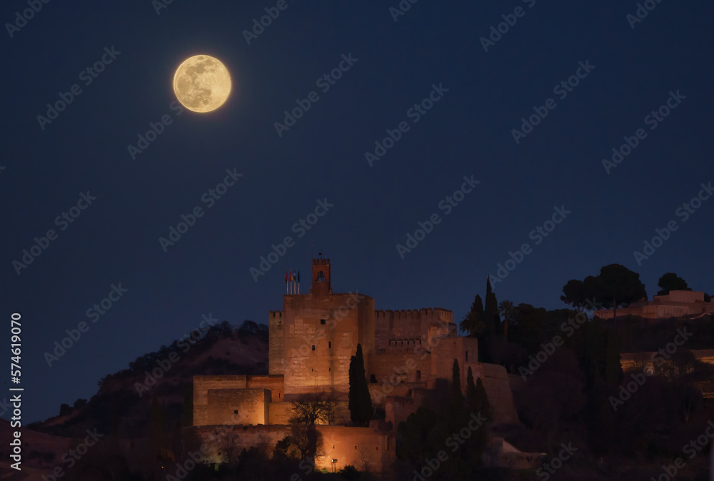 Alhambra of Granada illuminated at night, full moon creating magical ...