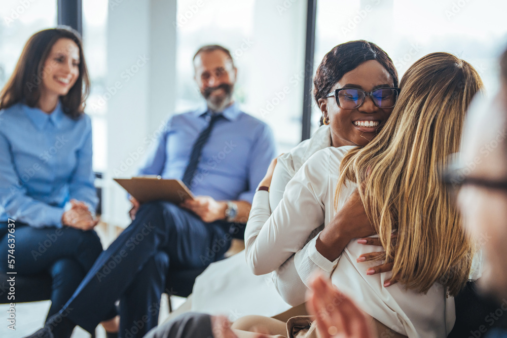 Caring female counselor hugs a female patient during a group therapy ...