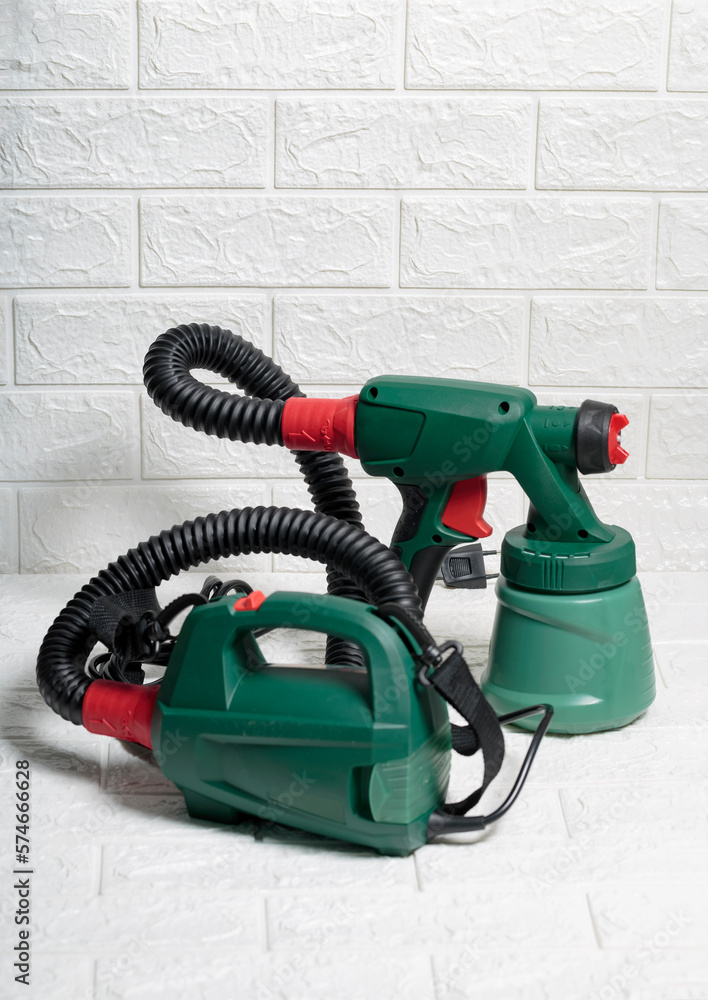 Electric green colored paint sprayer over a white brick background ...