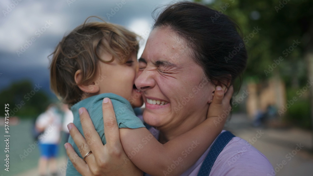 Funny cute moment of child kissing mother in cheek with tongue. Real ...