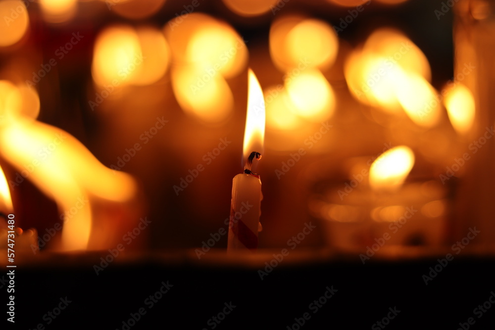 Solitary candle with others around it consuming itself with yellow and ...