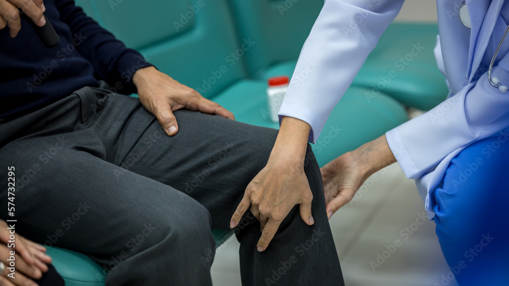 Doctor physiotherapist examining treating injured knee of senior ...