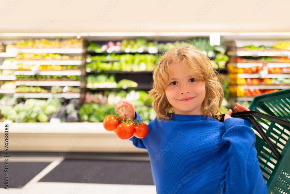 Child with fresh tomato vegetables. Portrait of child in a food store ...