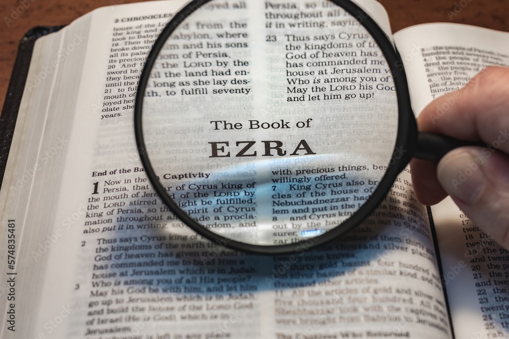 title page book of ezra close up using magnifying glass in the bible or ...
