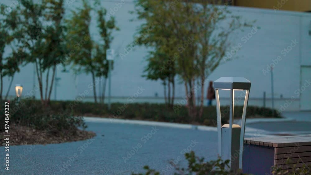 Urban design pedestrian bollard street light illuminated at dusk in a ...