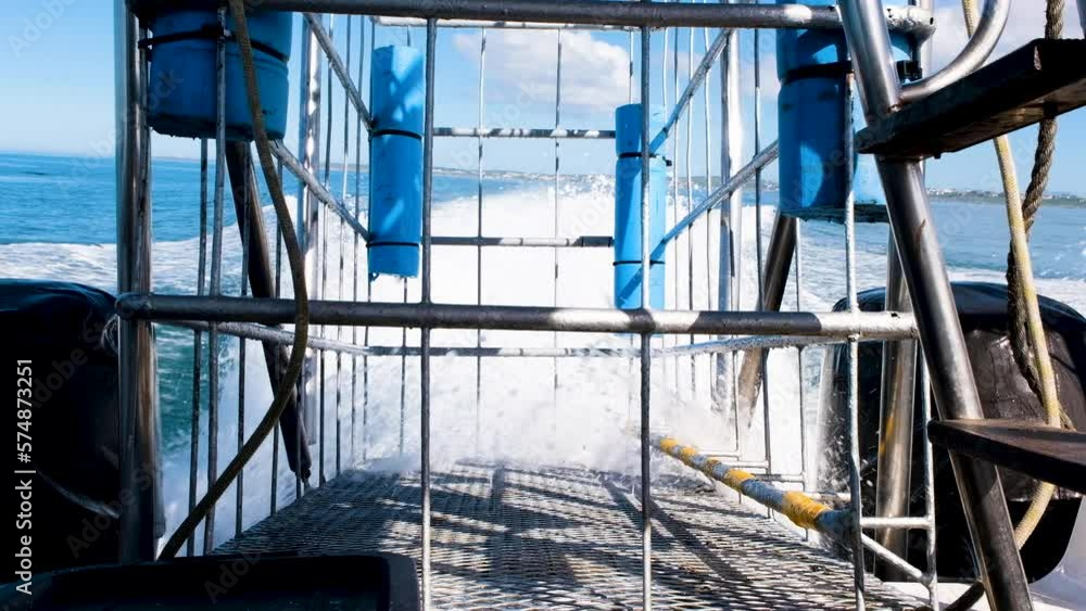Shark cage diving boat speeds out to sea, backwards view of cage ...