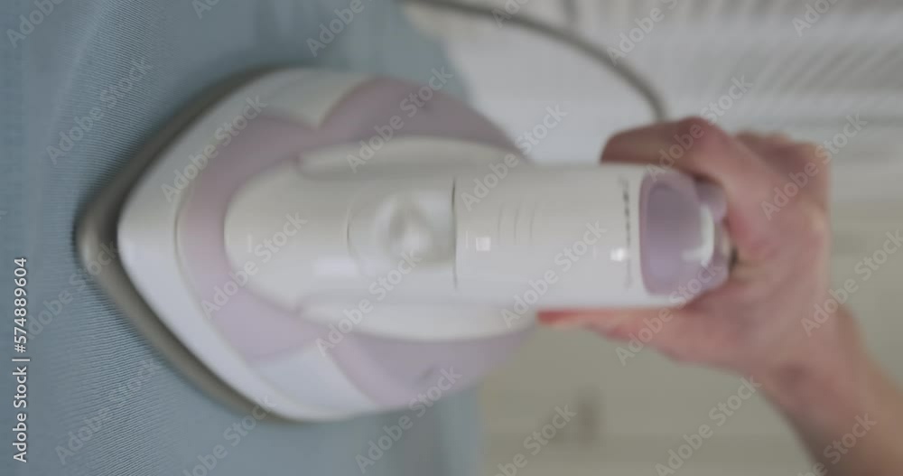 Sharp movements of the iron, vertical video, front view, close-up. The ...