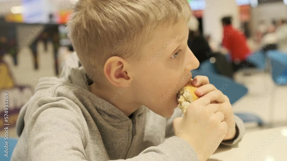 Cute boy eating burger. Hungry child in fast food cafe. Hungry child ...