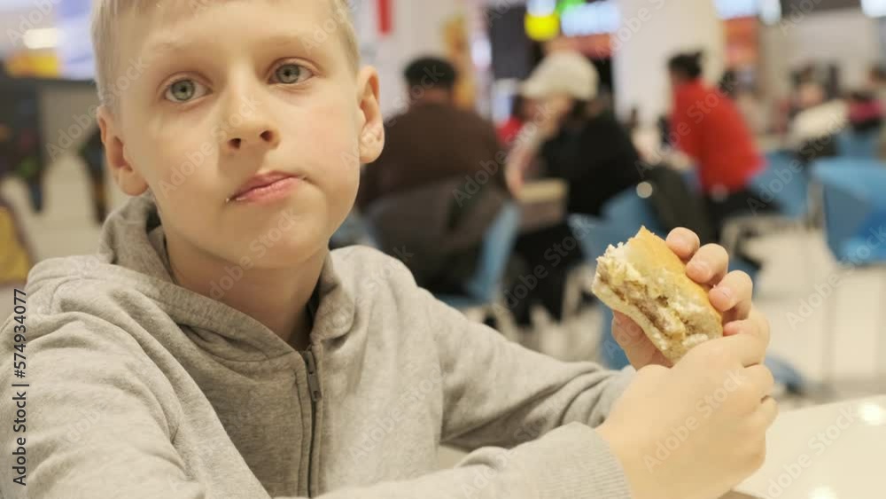 Cute boy eating burger. Hungry child in fast food cafe. Hungry child ...