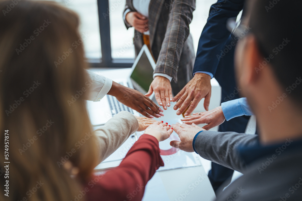 Top view of creative professionals putting their hands together as a ...
