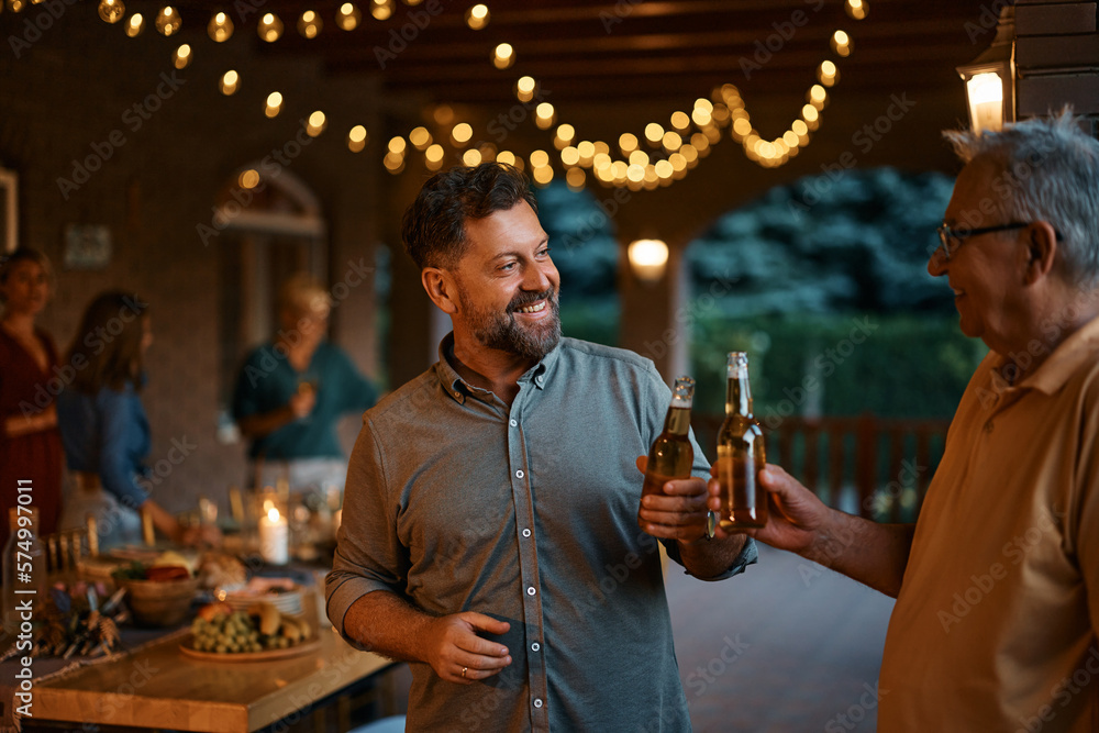 Happy man and his senior father toast with beer during family gathering ...