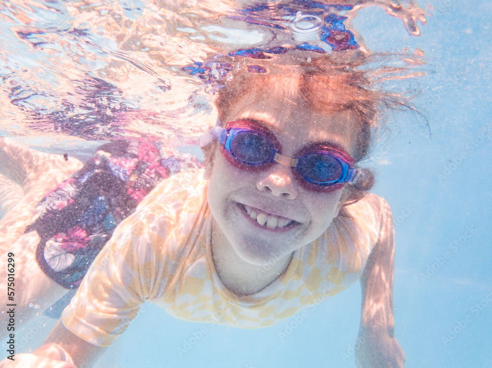 Smiling young Australian girl swimming in pool with goggles on in ...