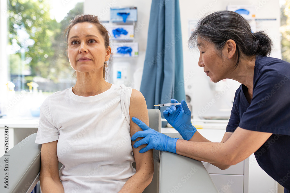 Female patient getting an injection on the arm by a female healthcare ...