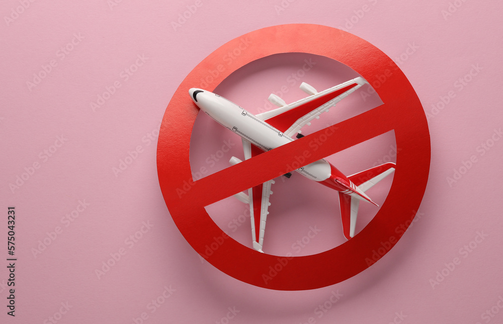 Flight ban. Model of passenger plane with prohibition sign on pink ...