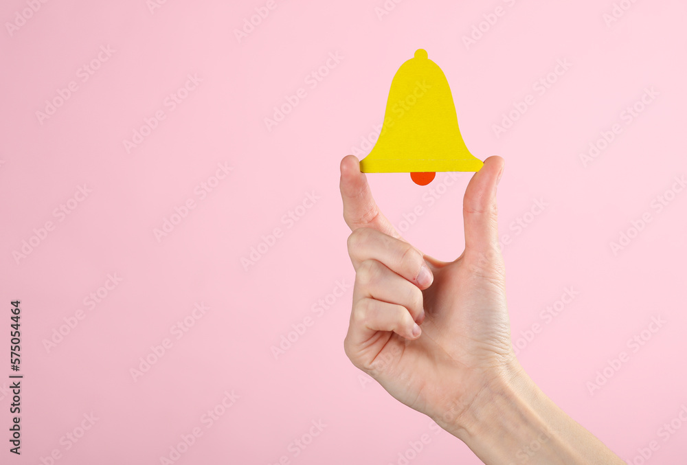 Hand holding paper cut notification bell on pink background. Social ...