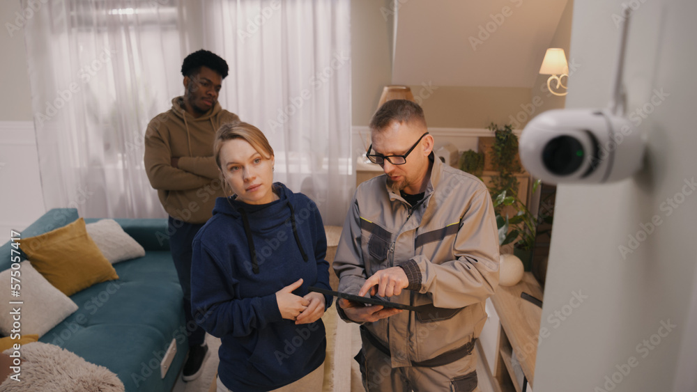 Installer sets up security camera at home of multi ethnic family using ...