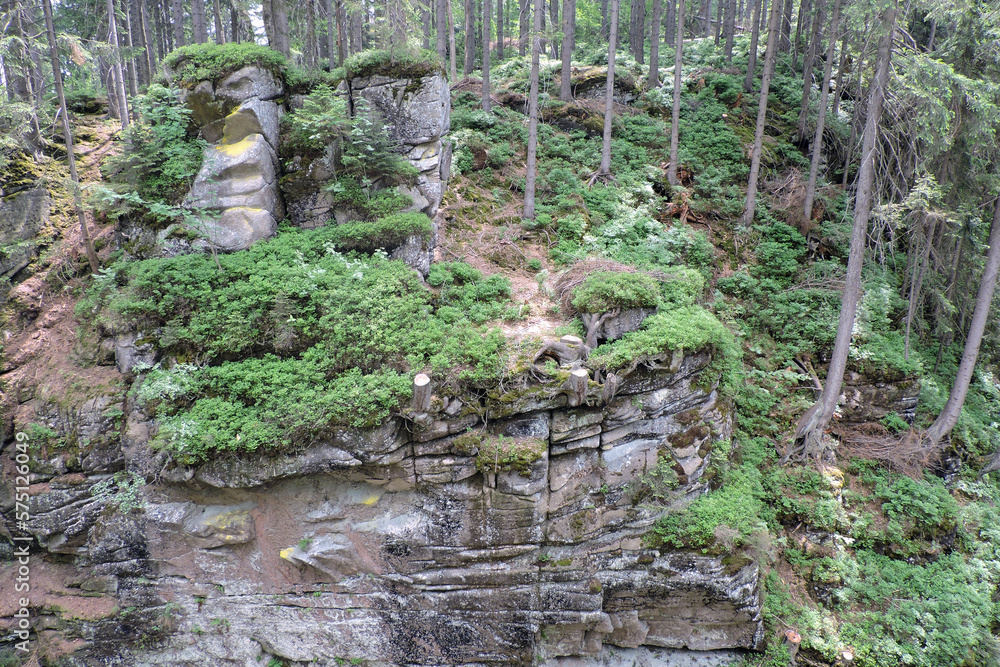A steep rocky wall made of naturally cracked granite rocks covered with ...