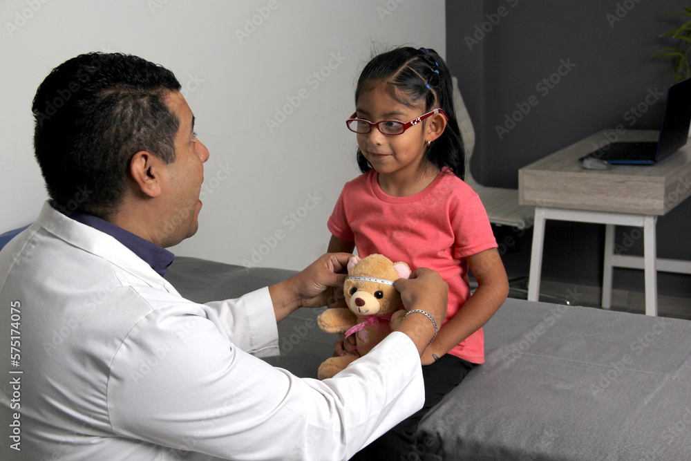 Latino pediatrician doctor checks his girl patient with autism spectrum ...