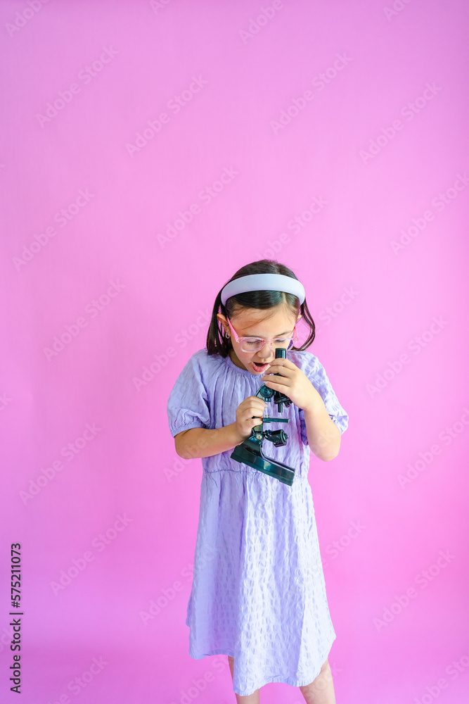 Pretty little girl looking through a compound microscope with a ...