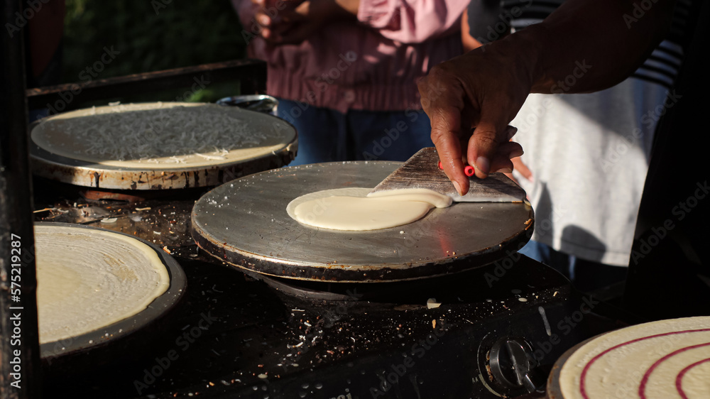 Making of crepes pancakes in street food center. A hand is making ...