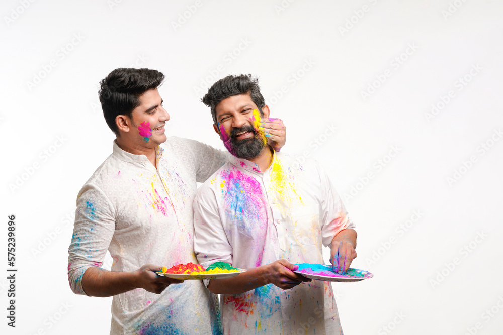 Two indian man applying color to each other and celebrating holi ...