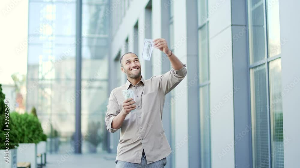 Excited crazy young adult man throwing dollar bills in the air while ...