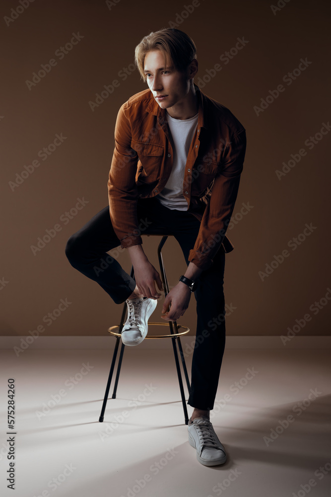 male model pose on barstool lean forward and look to side while being ...