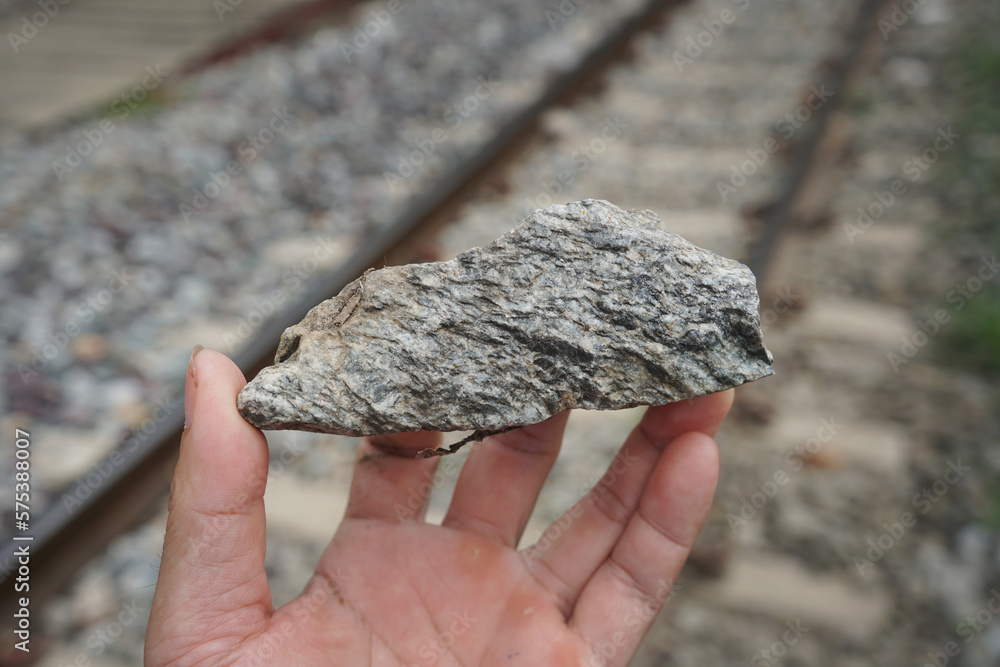 A fragment of raw granite rock on hand. Granite is a coarse-grained ...