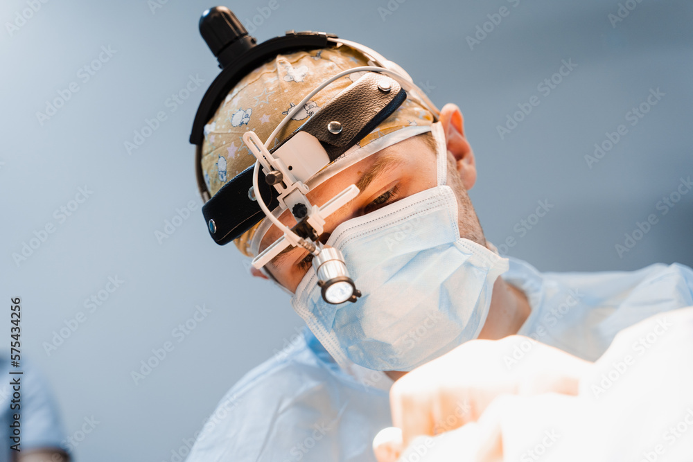 Surgeon with headlight is working in operating room. Blepharoplasty ...