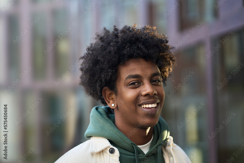 Smiling positive young African American guy model standing at big city ...