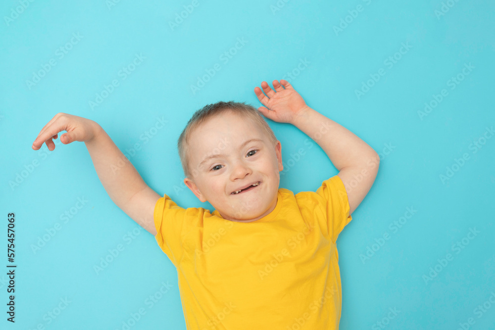 Cute little boy lies on a blue background in his yellow t-shirt and ...