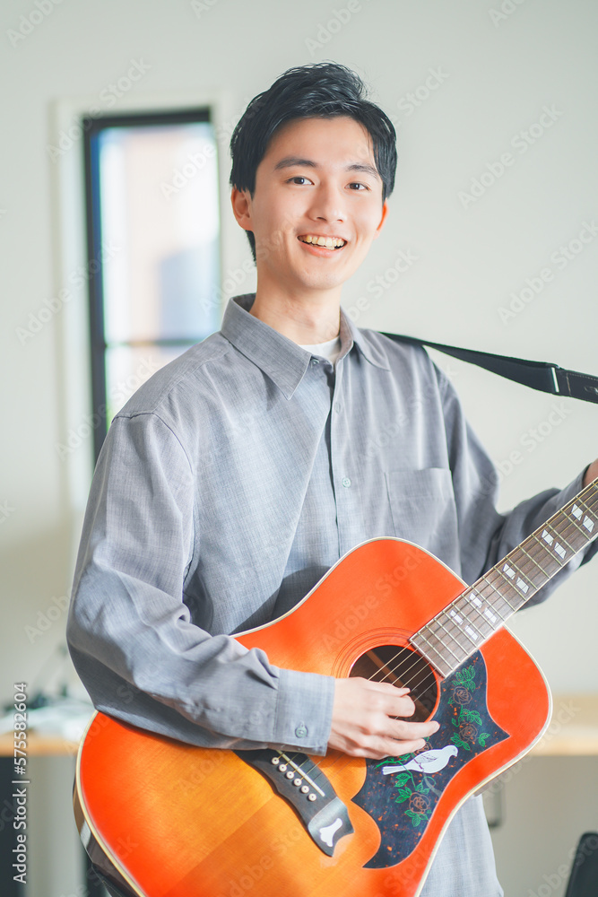 自宅でアコースティックギターを弾く若い男性 Stock Photo | Adobe Stock