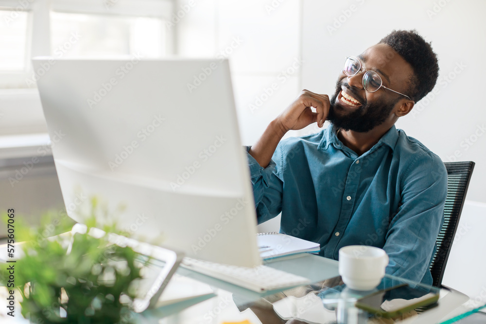Happy black male manager sitting at office desk in front of computer ...
