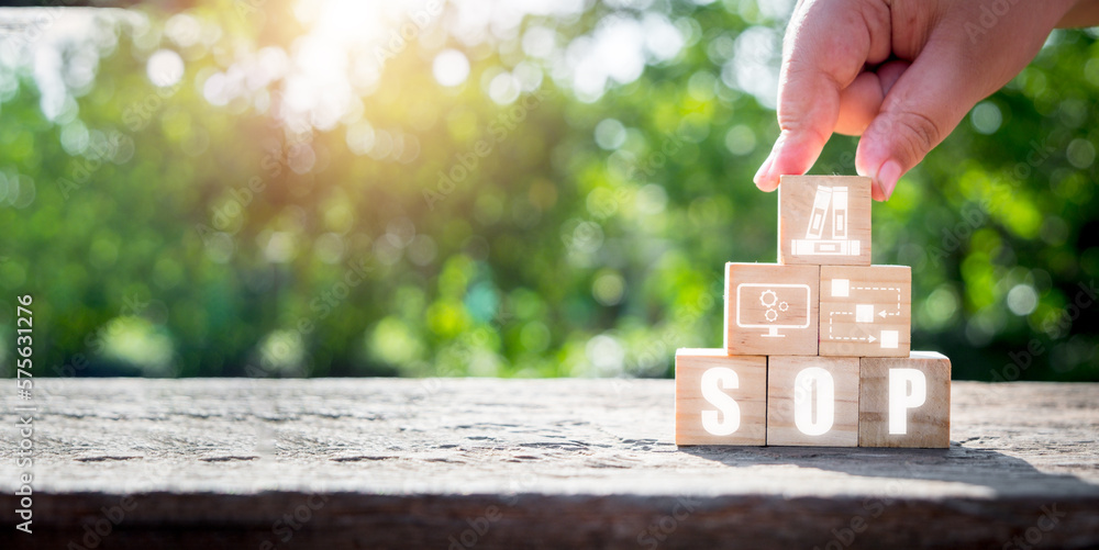 SOP, Standard Operating Procedure concept, Hand holding wooden block ...