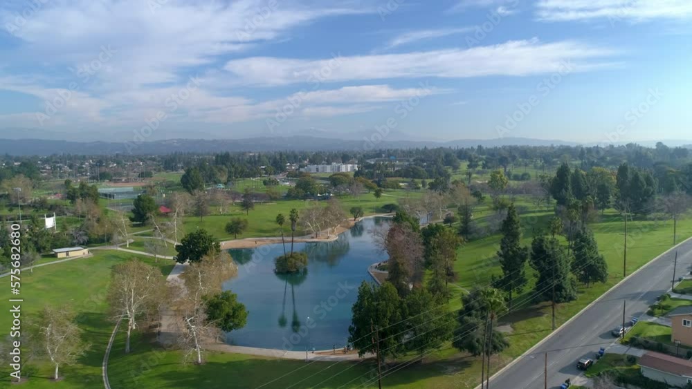 Aerial Forward Descending Shot Of Pond In Park Against Sky By City ...