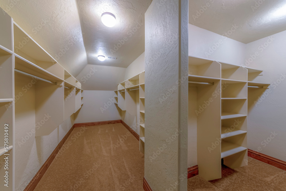 Foto de Large walk-in closet interior with shelving units on each two ...