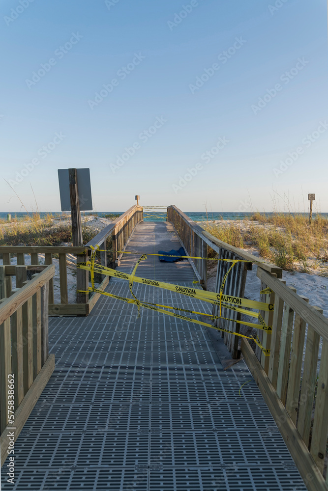 Closed boardwalk path with yellow tape caution barrier at the beach in ...