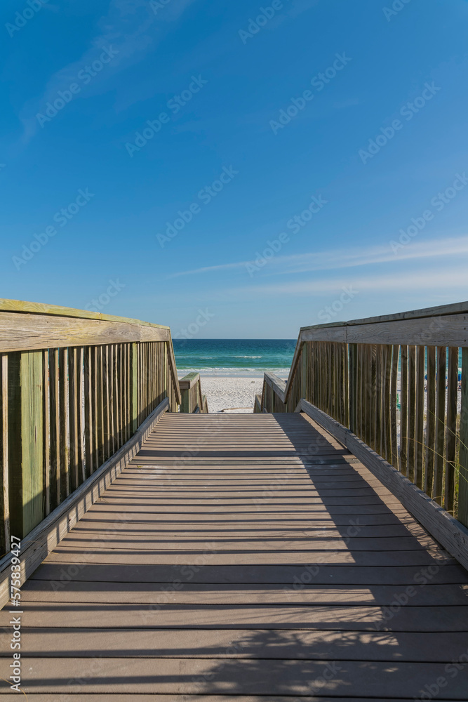 Wooden footbridge with handrails heading to the beach with white sand ...