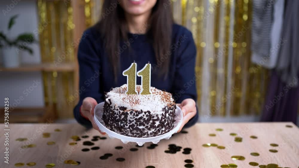 Kids birthday party. Woman mother holding cake with candle number 11 ...