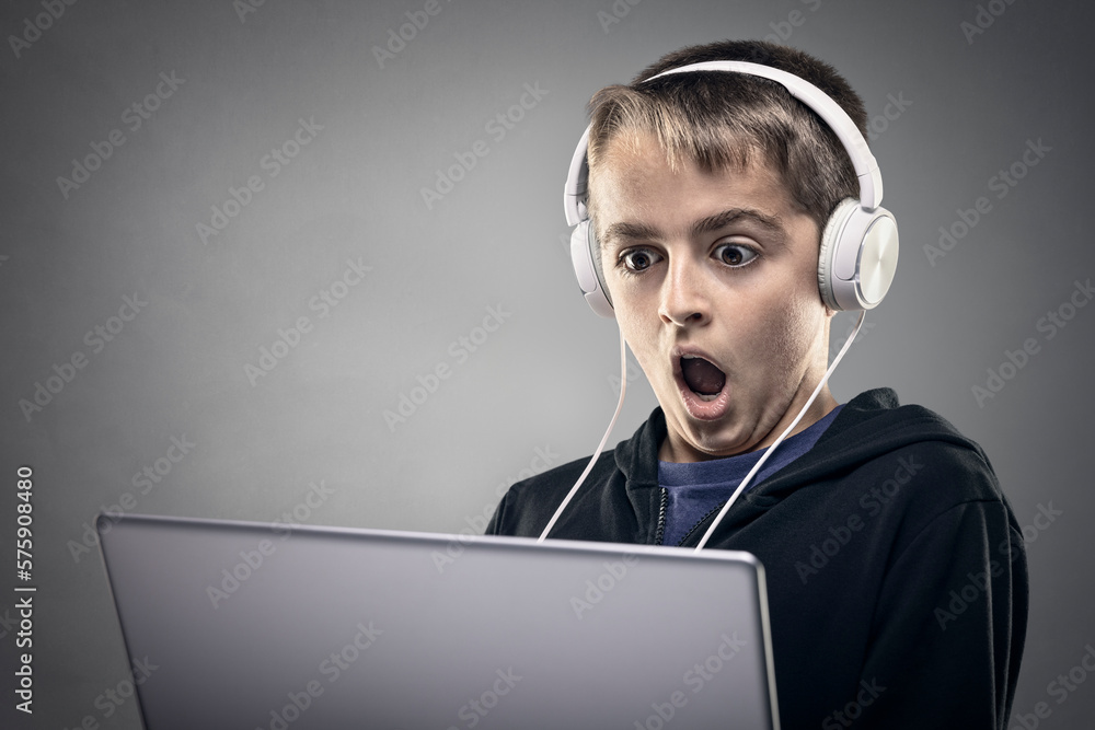Shocked and surprised teenag boy on the internet with laptop computer ...
