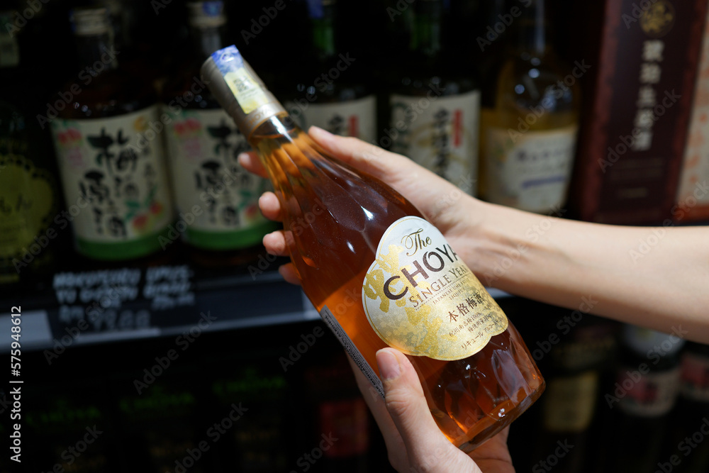PENANG, MALAYSIA - 22 FEB 2023: Adult hands holding a bottle of Choya ...