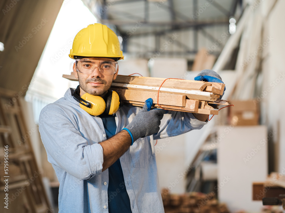Male carpenter carrying wood planks on his shoulder. Portrait of young ...