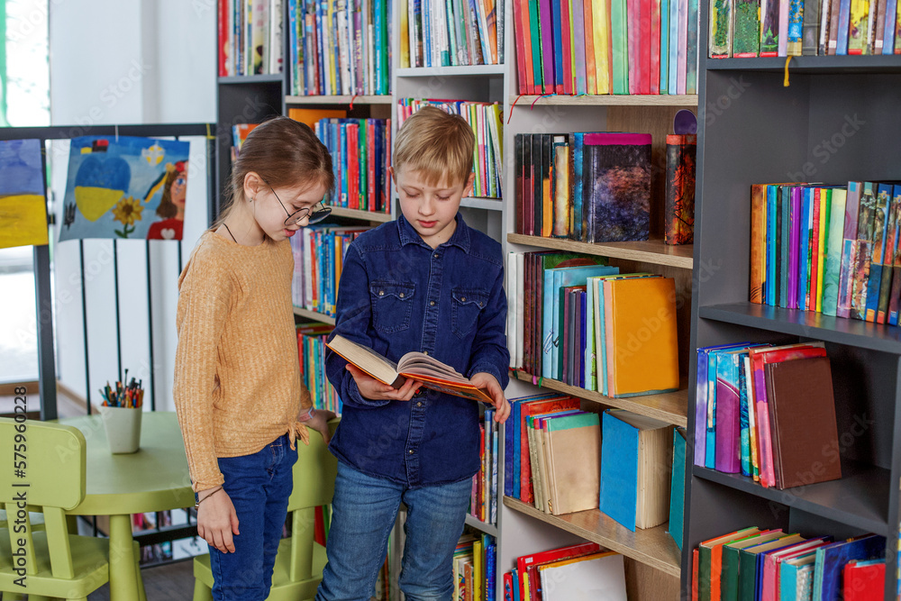Cute little children reading books in library. Concept of studying ...