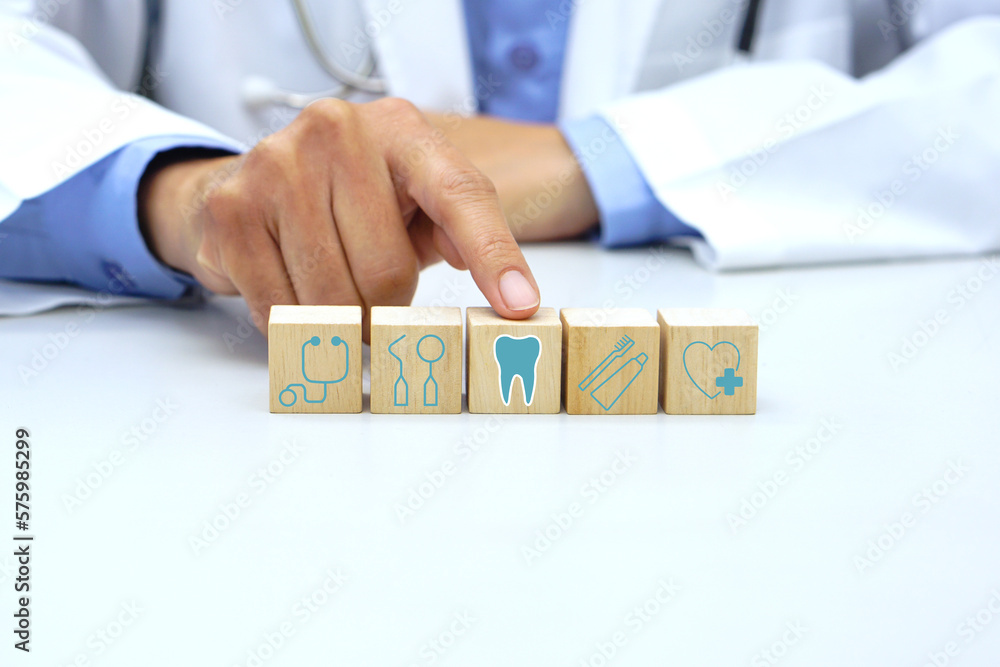 Finger of doctor touching a wooden block cube with tooth medical icon ...