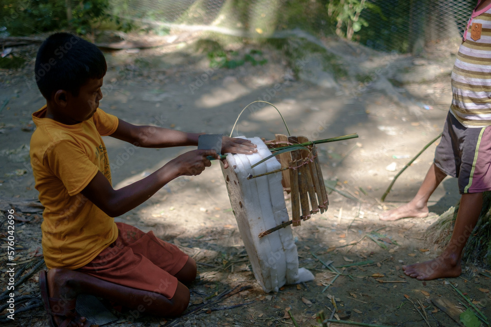 Village kids of Bangladesh making raft by sticks and cork sheet , hobby ...