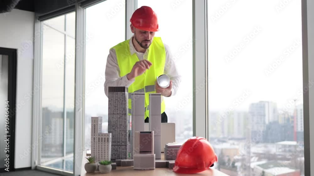 Engineer man in orange helmet and reflective vest standing near table ...